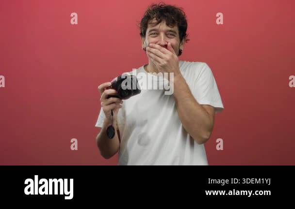 Hispanic man laughing with a camera in hand against a bold red ...