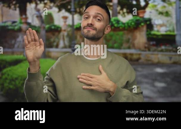 Young man in green sweater makes oath gesture in park outdoors with ...