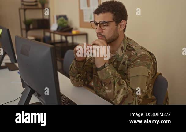 Soldier in camouflage uniform pinches nose while seated at computer ...