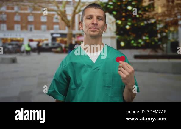 Man in green uniform holds red paper heart and makes ok gesture ...