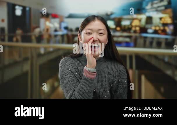 Woman shouting in a bustling mall with vibrant stores in the background ...