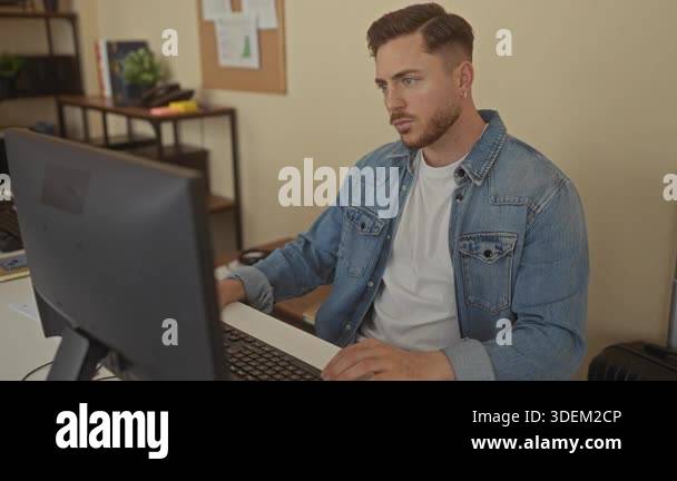 Young man with beard working in an office environment, focused on ...