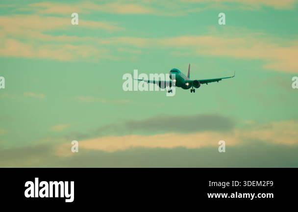 Plane flying in evening sky with sunset clouds in background. Airliner ...