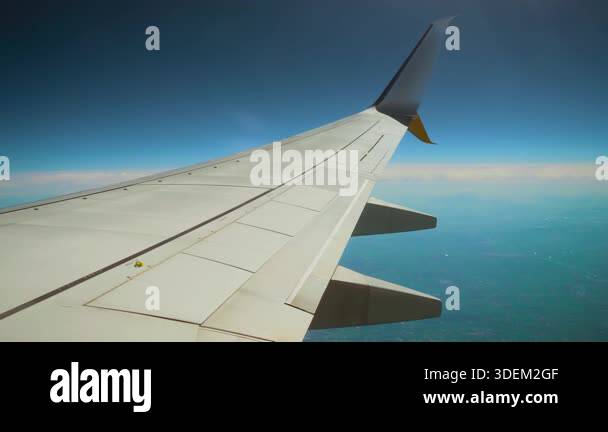 Airplane wing flying above ground, flaps ailerons winglet over haze and ...