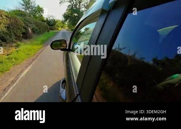 SUV traveling along quiet rural road on sunny morning. POV side view ...