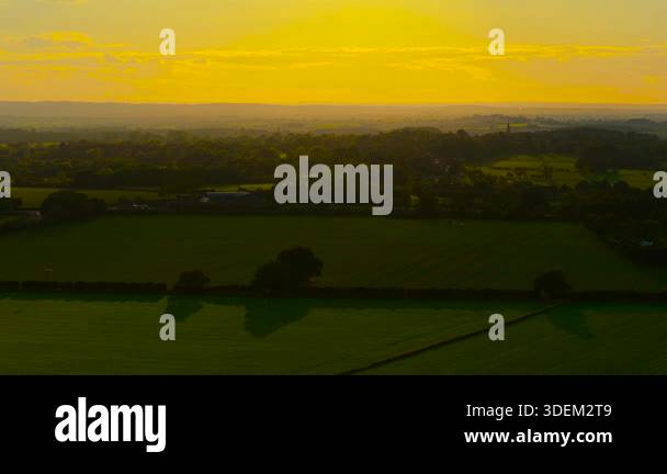 Vast farmland stretching under golden sunset over distant hills ...