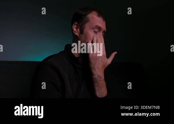 An emotional man covers his face with his hand, expressing sadness and ...