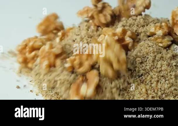 Whole walnut halves poured on crushed walnut kernels on white ...