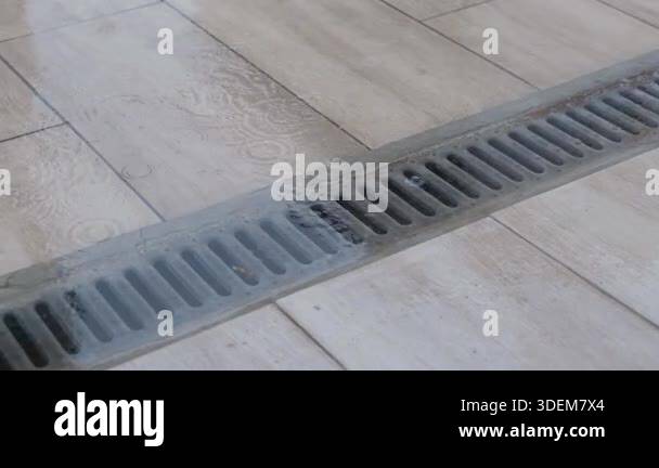 Clogged outdoor drainage grate with water pooling on tiled surface ...