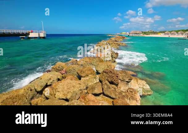 Beautiful view of Caribbean Sea with pier, rocky breakwater and waves ...