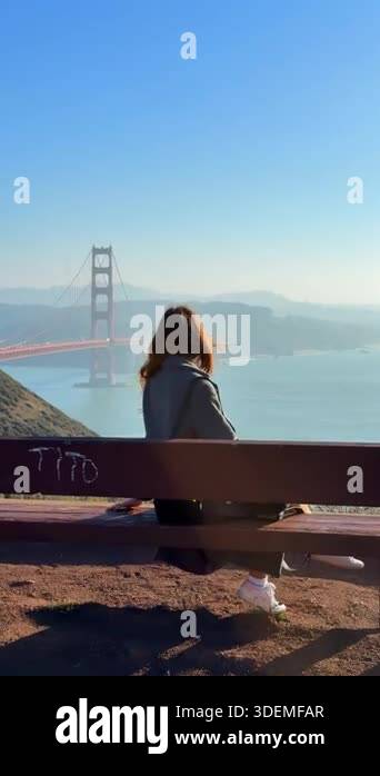 Young woman sitting on a bench overlooking Golden Gate Bridge in San ...