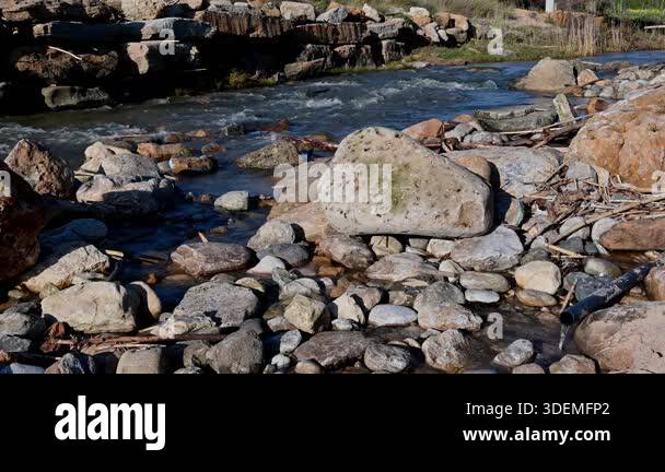 Flowing stream water moving between rocks and pebbles near the beach in ...
