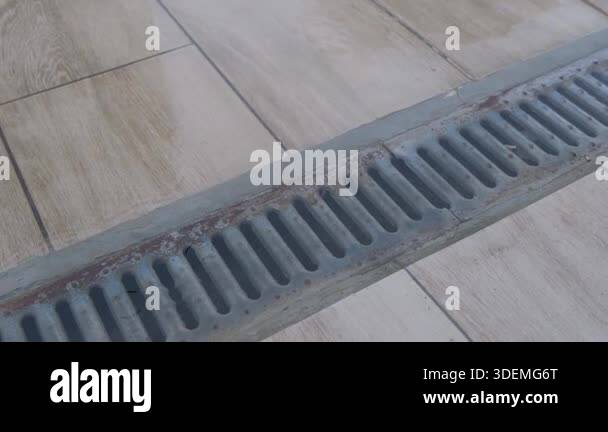 Clogged outdoor drainage grate with water pooling on tiled surface ...