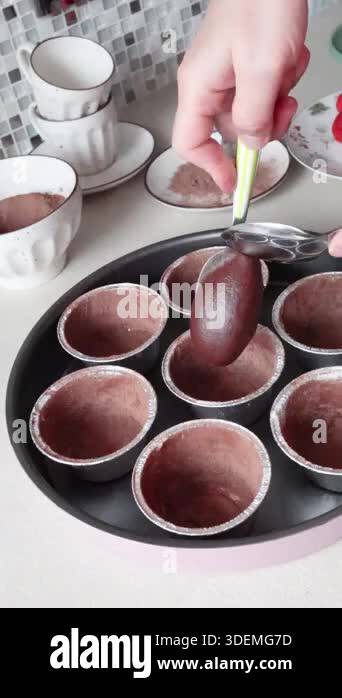 Anonymous person pours chocolate batter into foil molds. Homemade ...
