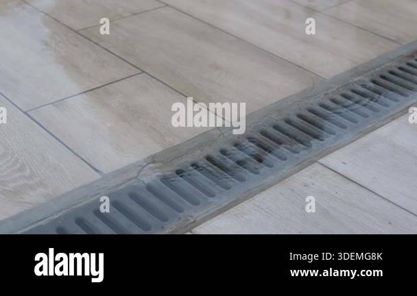 Clogged outdoor drainage grate with water pooling on tiled surface ...