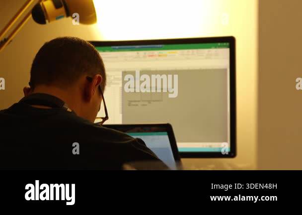 Over-the-shoulder view of man working at desk with large monitor ...