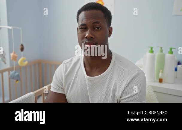 Handsome man in bedroom sitting near baby cradle with bottles on a ...