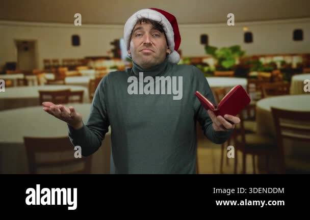 Man wearing christmas hat inside restaurant displaying open wallet in a ...