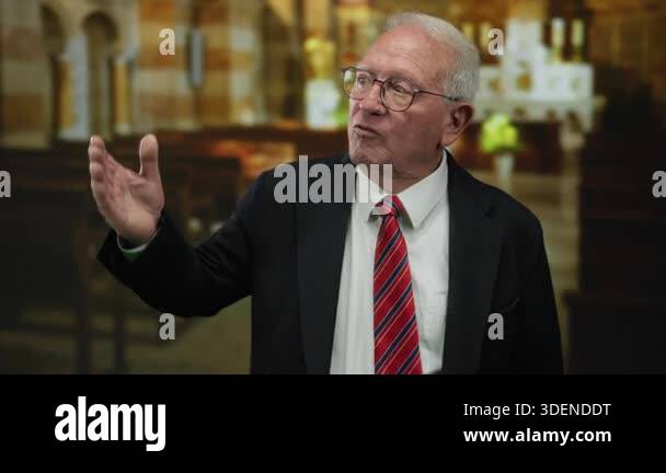 Senior man in a suit gestures passionately inside a church setting ...