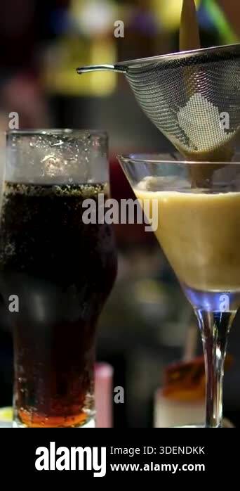 barista shaking iced black coffee in shaker and pouring in cocktail ...