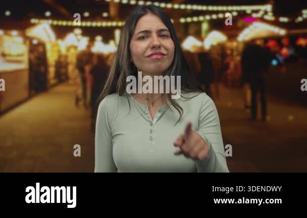 Young woman pointing finger at camera and tapping temple on crowded ...