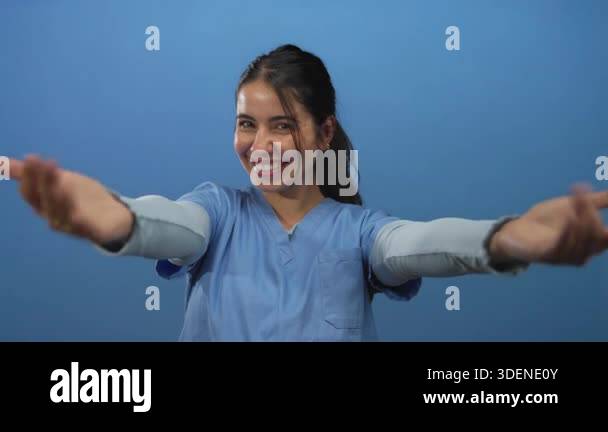 Woman smiling in hospital scrubs against isolated blue background ...