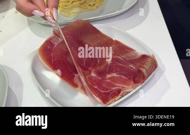 Person puts delicious serrano ham on a wooden plate. High quality 4k ...