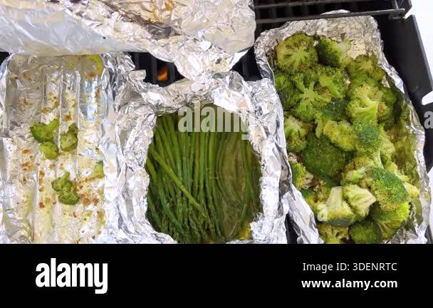 A closeup shows sliced carrots cooking inside a foil packet on an ...