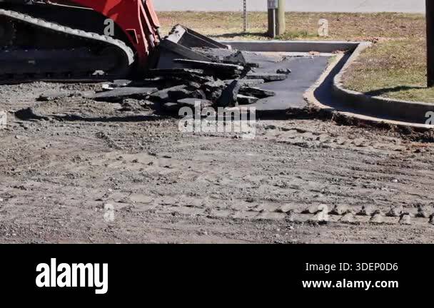 Heavy machinery is lifting removing broken asphalt pieces from ...