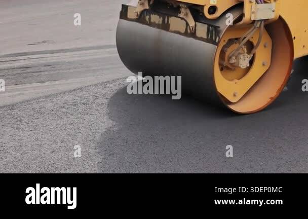 Heavy machinery is at work as roller compacts freshly laid asphalt on ...