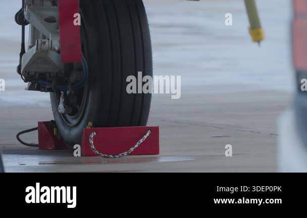 Close view of fighter jet landing gear wheel locked with chocks on wet ...