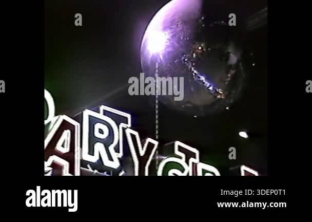 Colorful neon Party Street sign under large hanging disco ball in VHS ...