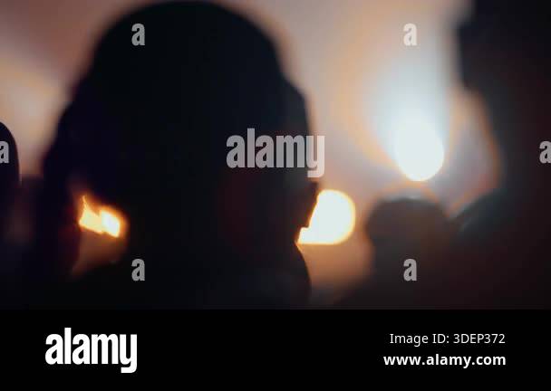 Silhouettes of audience hands raised during live concert with warm ...