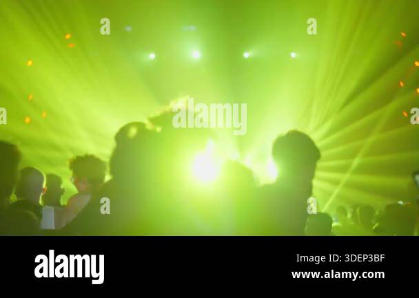 Audience stands shoulder to shoulder facing concert stage as powerful ...