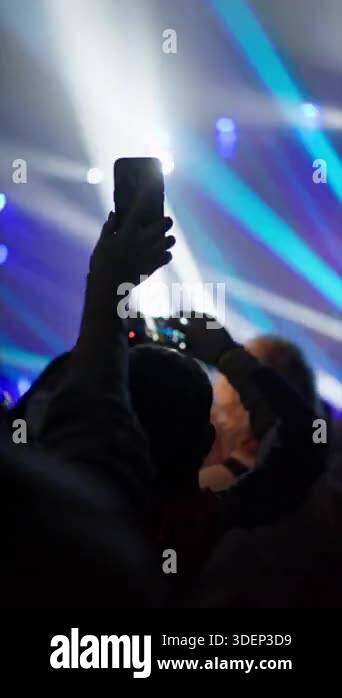 Vertical footage of audience filming live performance with bright ...