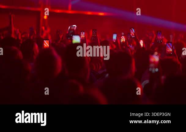 Slow motion audience jumping and dancing while filming live concert as ...
