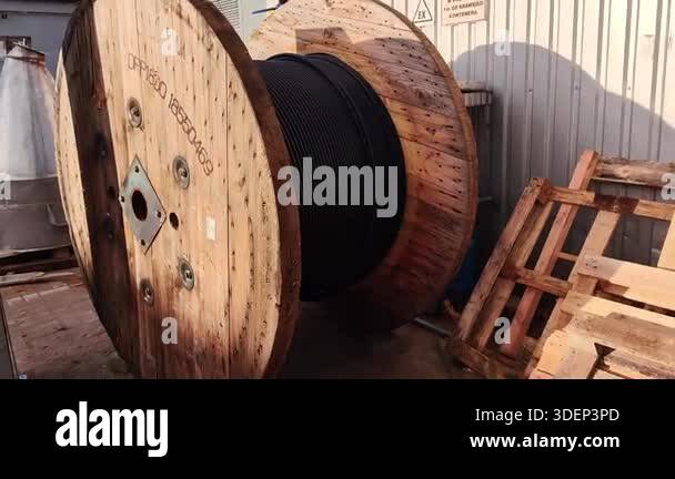 Large wooden cable drum with coiled industrial power cable outdoors ...