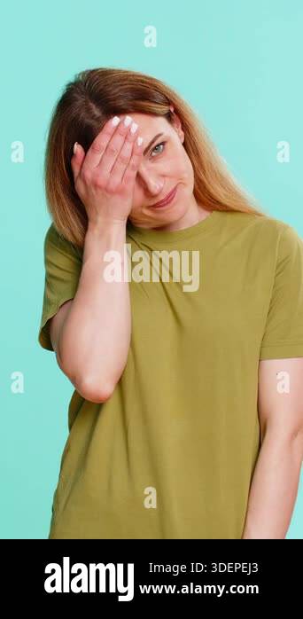 Middle-aged woman performs facepalm and rubs forehead, clearly showing ...