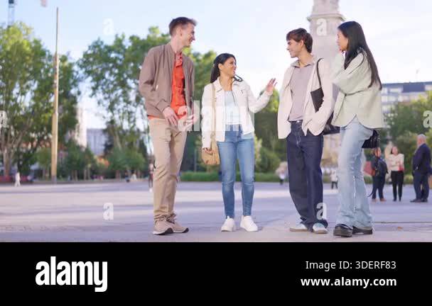 Multiethnic young friends standing together outdoors in a city, talking ...