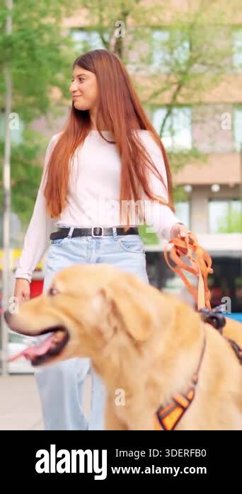 Two cheerful young women chatting and smiling while walking with their ...