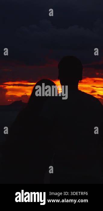 Vertical video. Couple Embraces Quietly While Watching a Fiery Sunset ...