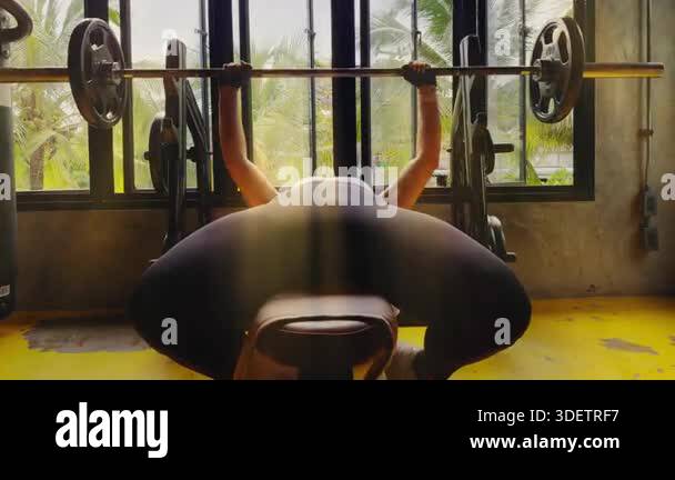 Front View of Woman Performing Bench Press with Barbell in Gym Facing ...