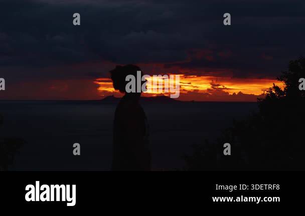 Man Approaches and Kisses Woman as They Stand in Silhouette Against a ...