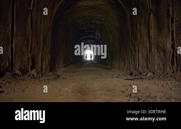 Man and Woman Walk Together from Bright Tunnel Entrance into Shadow ...