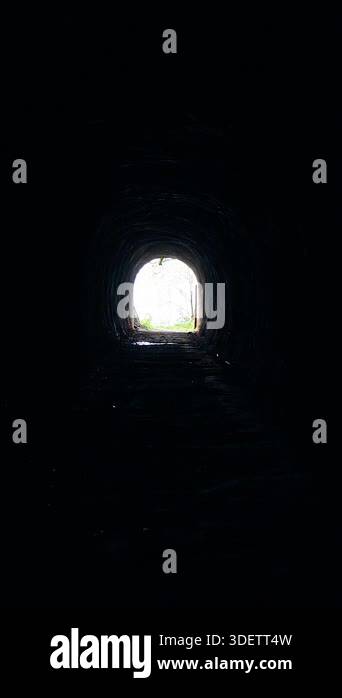 Vertical video. Dark Underground Tunnel with Natural Light at the End ...