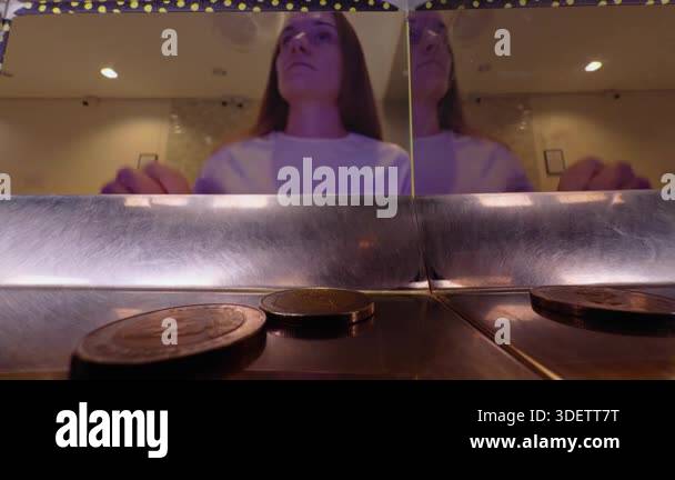 Woman in Warm Indoor Light Gathering Coins Through a Metal Slot Viewed ...