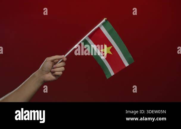 Man holding suriname flag against a vibrant red background, showcasing ...