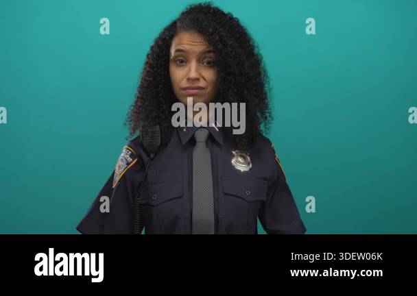 Hispanic female police officer in uniform poses against a green wall ...