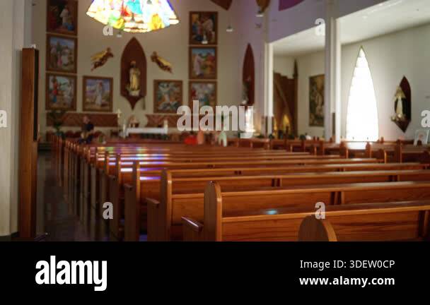 Wooden pews in soft shallow focus with blurred altar and stained glass ...
