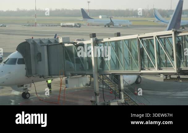 Travelers walking inside passenger boarding bridge to exit aircraft ...
